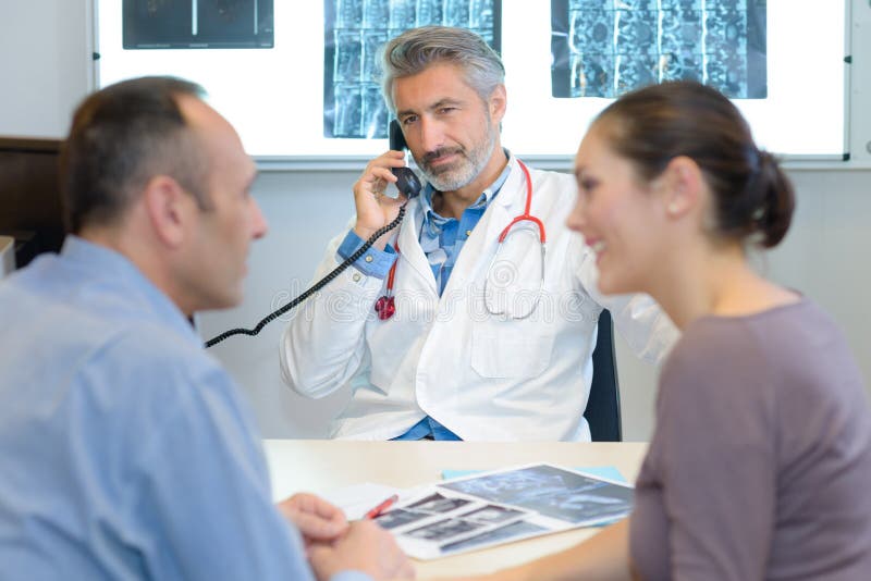 Couple with Doctor Talking on Telephone Stock Photo - Image of office ...
