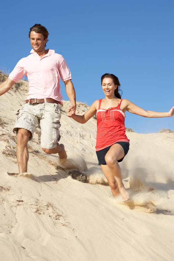 Couple Enjoying Beach Holiday Running Down Dune Stock Photo - Image of ...