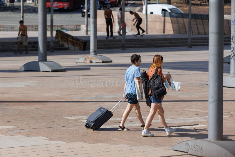 Couple of Girls with a Backpack and Trolley Walking through a Square ...