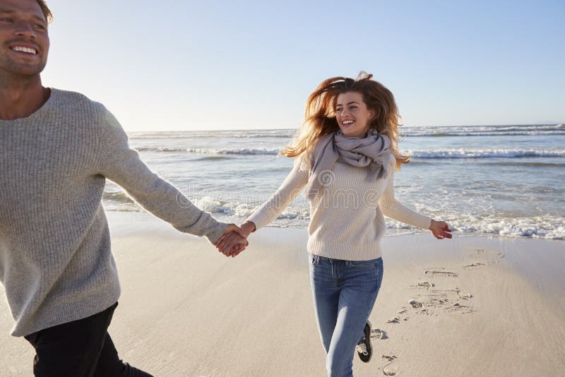 Couple Having Fun Running Along Winter Beach Together Stock Photo ...