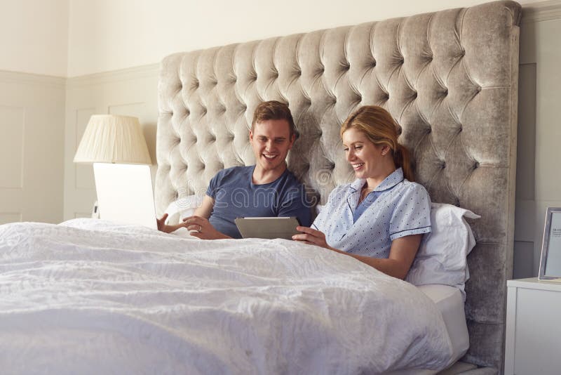 Couple at Home in Bed Self Isolating Using Digital Tablet and Mobile ...