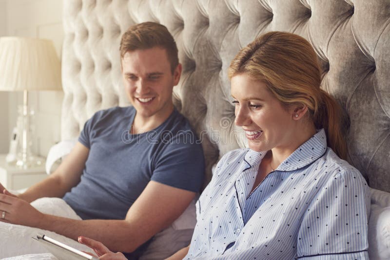Couple at Home in Bed Self Isolating Using Digital Tablet and Mobile ...
