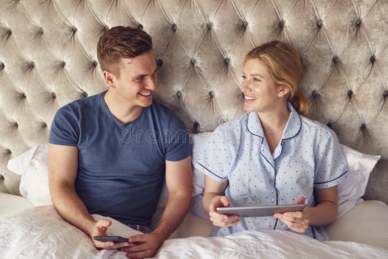 Couple at Home in Bed Self Isolating Using Digital Tablet and Mobile ...