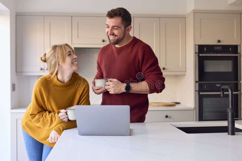 Couple at Home Looking at Laptop on Counter in Kitchen Together Stock ...