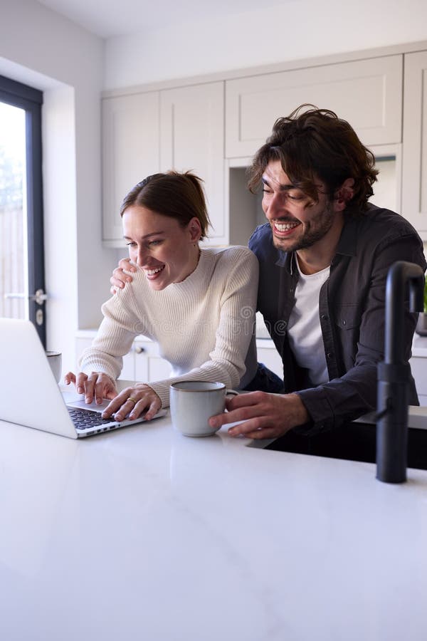 Couple at Home Looking at Laptop on Counter in Kitchen Together Stock ...