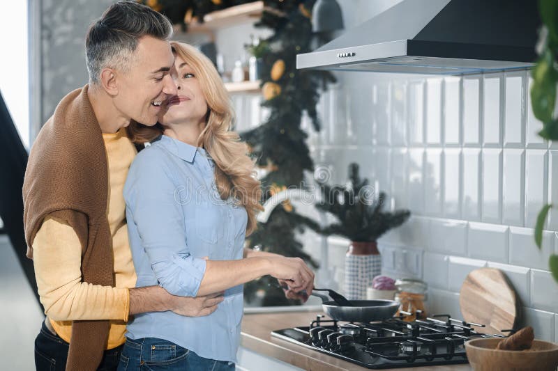 A Couple Hugging in the Kitchen and Looking Happy Stock Image - Image ...