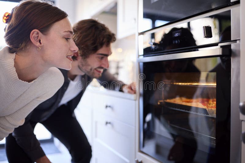 Couple in Kitchen at Home Watching Homemade Pizza in Oven Baking Stock ...