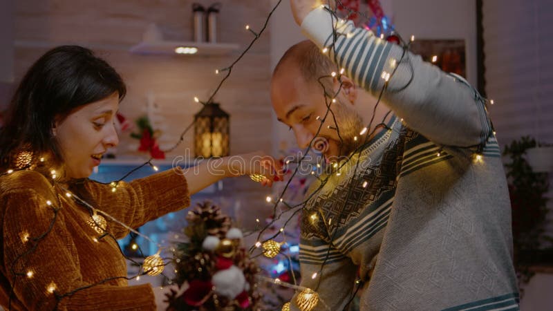 Couple Laughing Getting Tangled in String of Festive Lights Stock Video ...