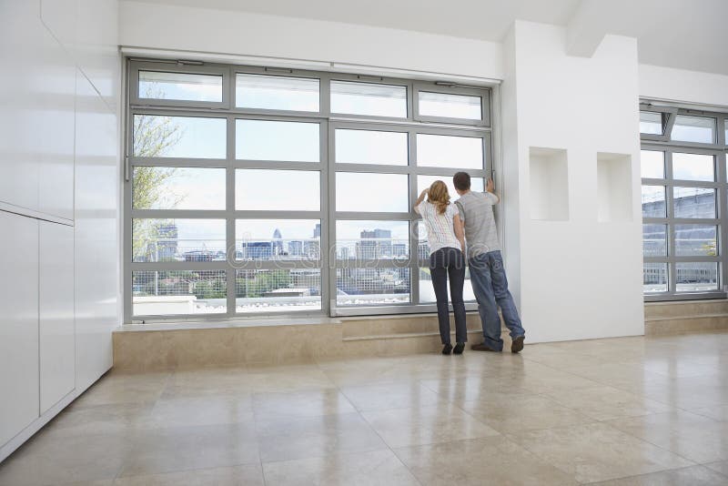 Couple Looking Out of Window in Empty Apartment Stock Photo - Image of ...