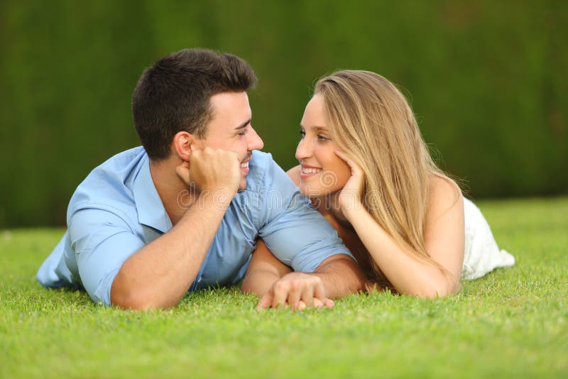 Couple In Love Dating And Looking Each Other Lying On The Grass Stock
