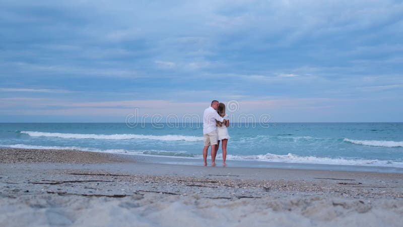 A Couple in Love Hugs by the Water, while Relaxing on the Ocean Stock ...
