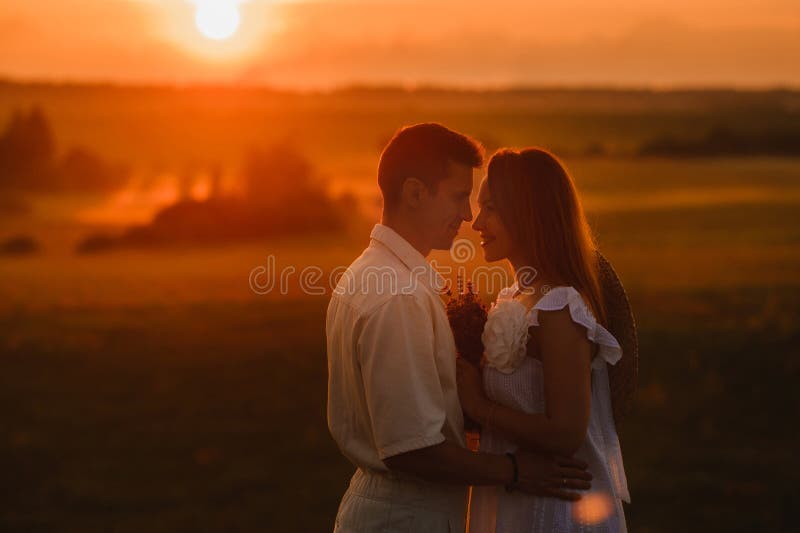 A Couple in Love in White Clothes in a Field at a Red Sunset Stock ...