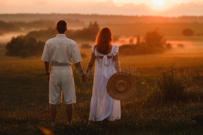 A Couple in Love in White Clothes in a Field at a Red Sunset Stock ...