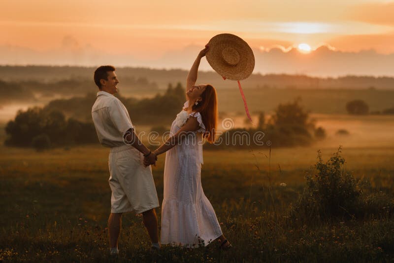 A Couple in Love in White Clothes in a Field at a Red Sunset Stock ...