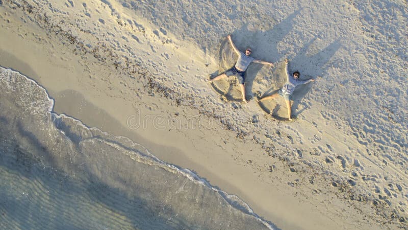 A Couple Making Angels on the Sand at Sunset, Aerial Stock Photo ...