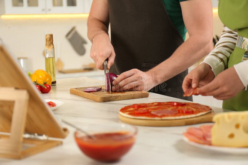 Couple Making Pizza Together while Watching Online Cooking Course Via ...