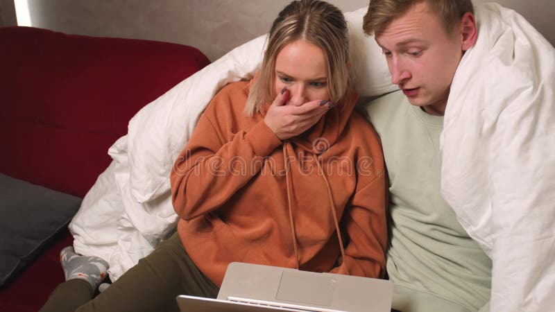 The Couple Man And Woman Watching A Movie On A Laptop On Sofa At Home