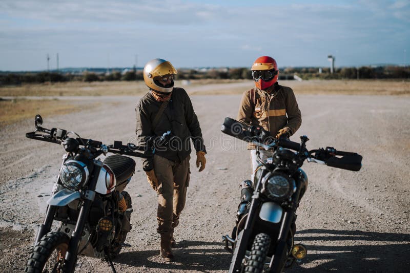 A Couple of Motorcyclists Standing Next To Each Other on a Road Stock ...
