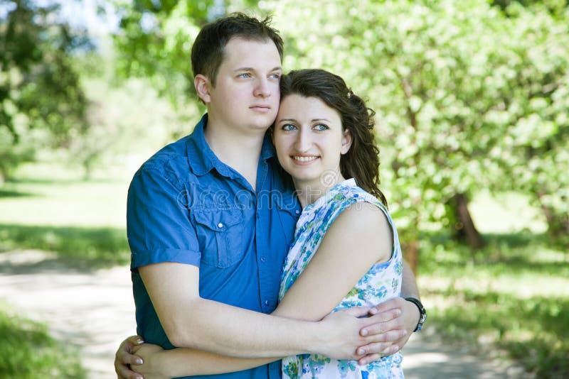 Couple Outdoors Looking Forward Stock Photo - Image of embracing, green ...