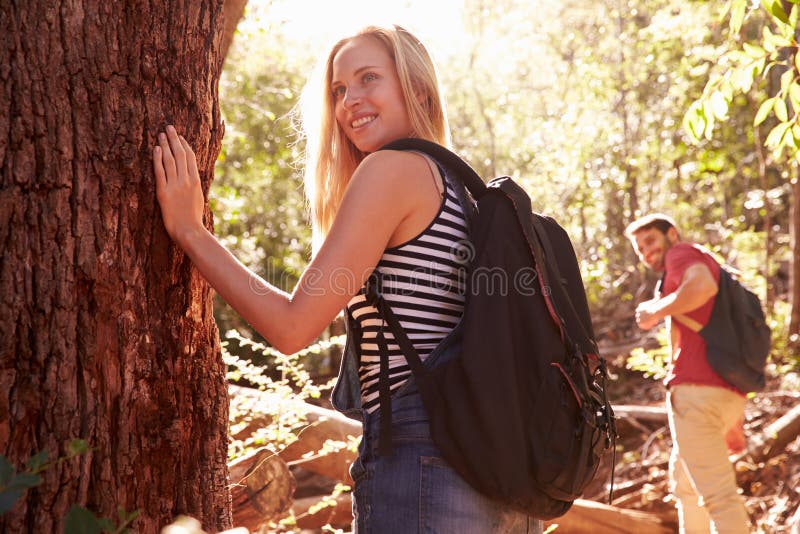 Couple Pausing by Tree Trunk in on Walk through Forest Stock Photo ...