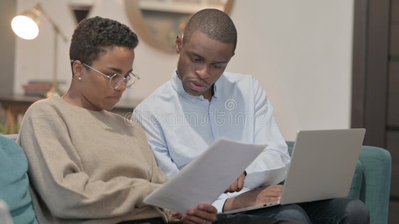 Couple Reading Documents while Working on Laptop, on Sofa Stock Image ...