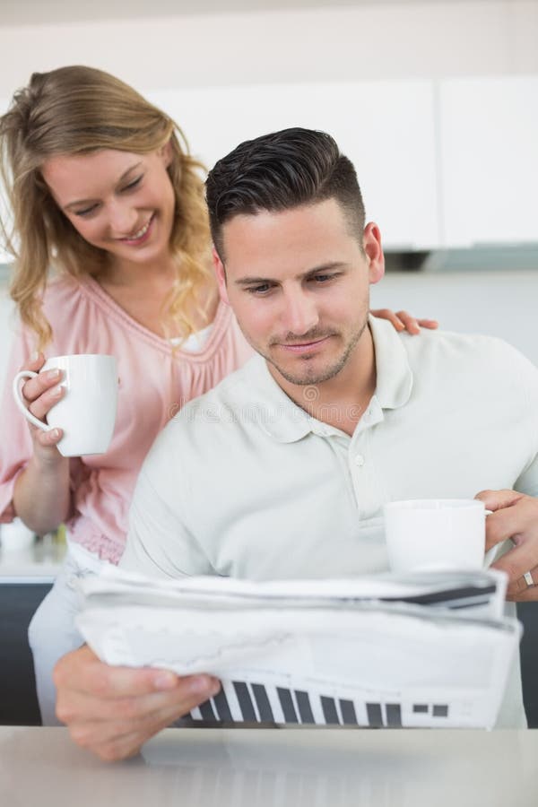 Couple Reading Newspaper while Holding Coffee Mugs Stock Photo - Image ...