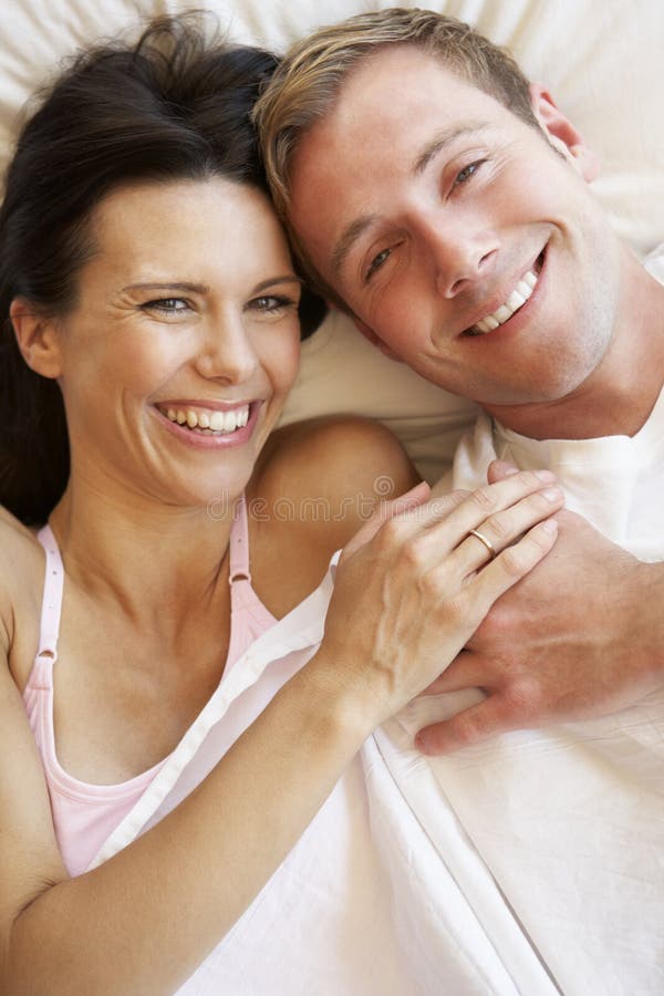 Couple Relaxing in Bed stock photo. Image of peaceful - 54971682