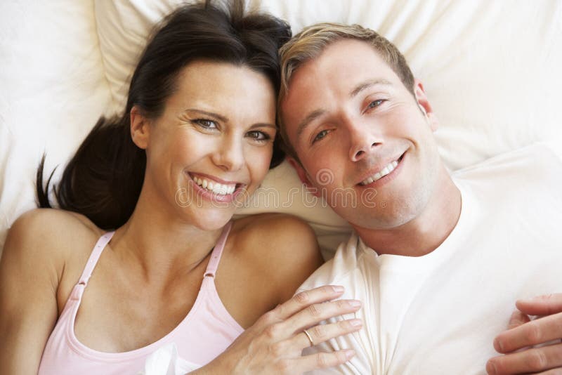Couple Relaxing in Bed stock photo. Image of cuddling - 55896674