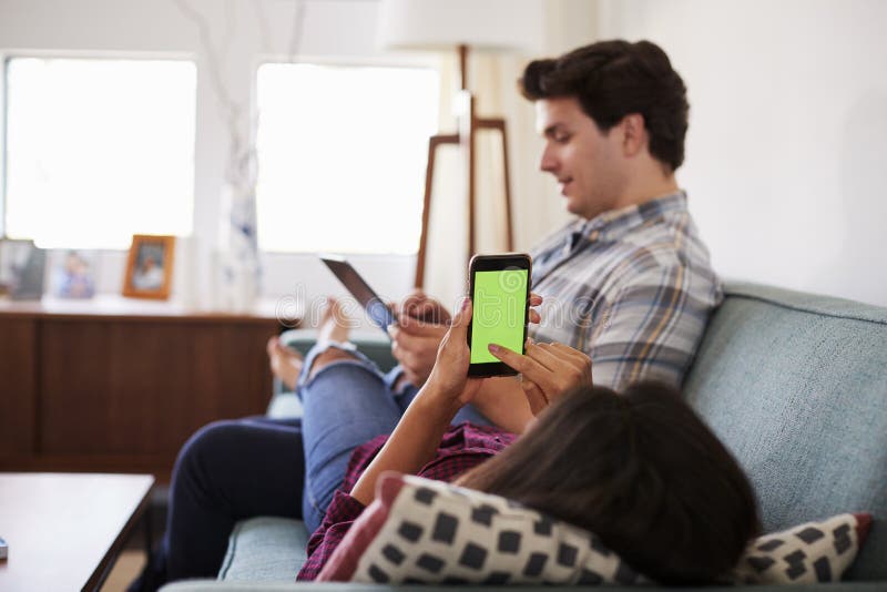 Couple Relaxing on Sofa at Home Using Mobile Phone and Digital Tablet ...