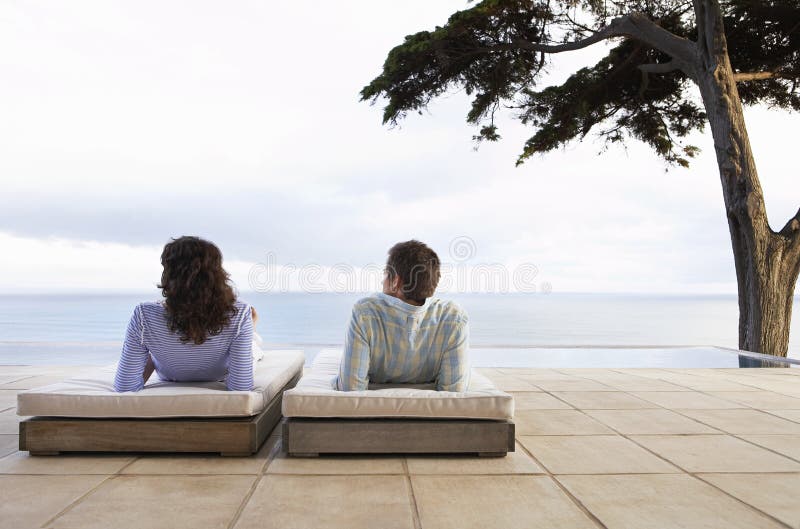 Couple Relaxing on Sunbeds by Infinity Pool Stock Image - Image of ...