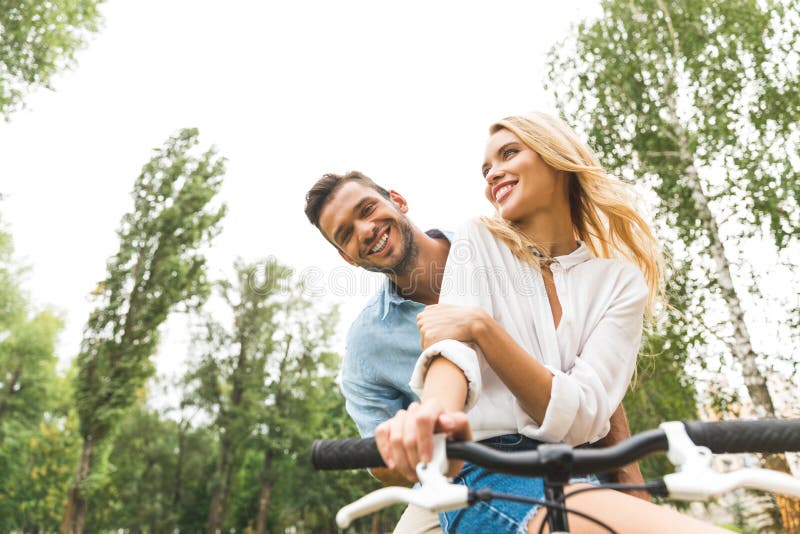 Low Angle View of Smiling Couple Riding Bicycle Together Stock Image ...