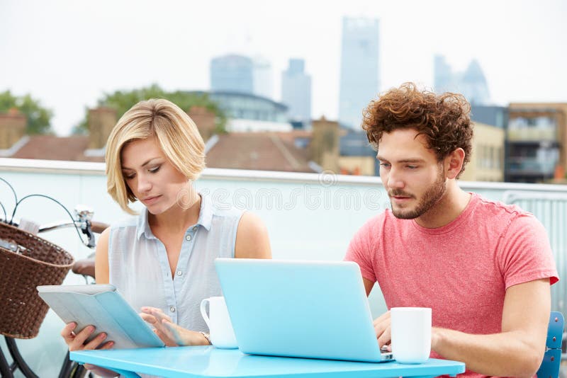 Couple on Roof Terrace Using Laptop and Digital Tablet Stock Photo ...