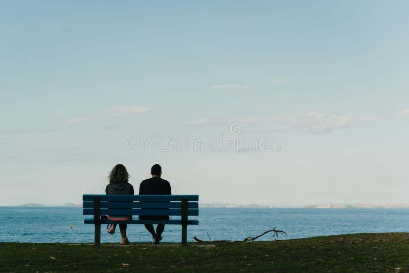 Couple Sits on a Bench Overlooking a Stunning Beach Stock Photo - Image ...