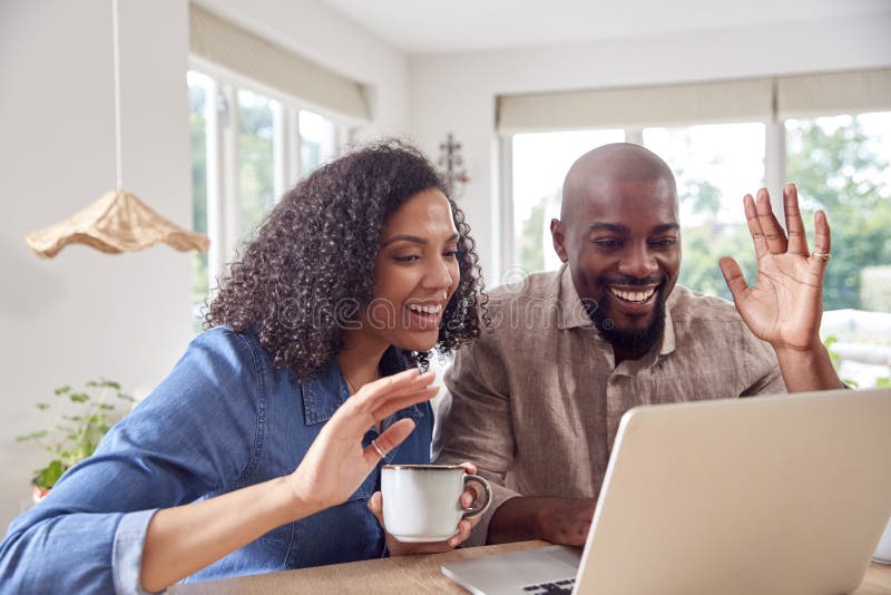 Couple Sitting Around Table at Home Making Video Call on Laptop Stock ...