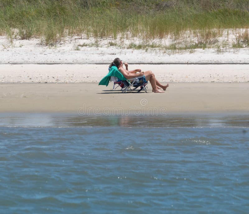 Couple Sitting in a Beach Chair on Grassy Shore Stock Image - Image of ...