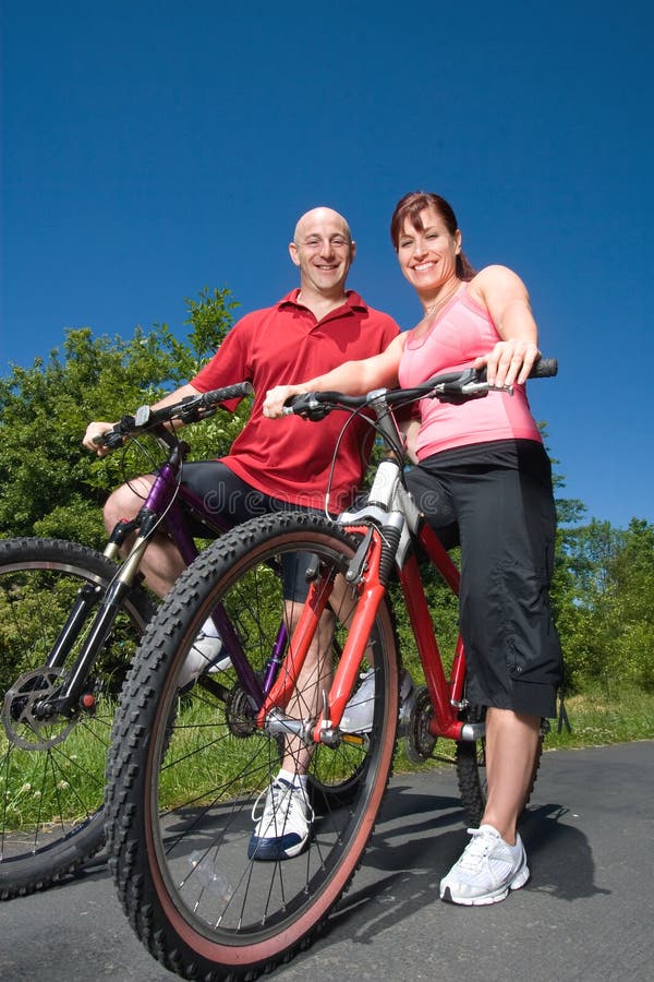 Couple Sitting on Bikes - Vertical Stock Photo - Image of seated, bond ...