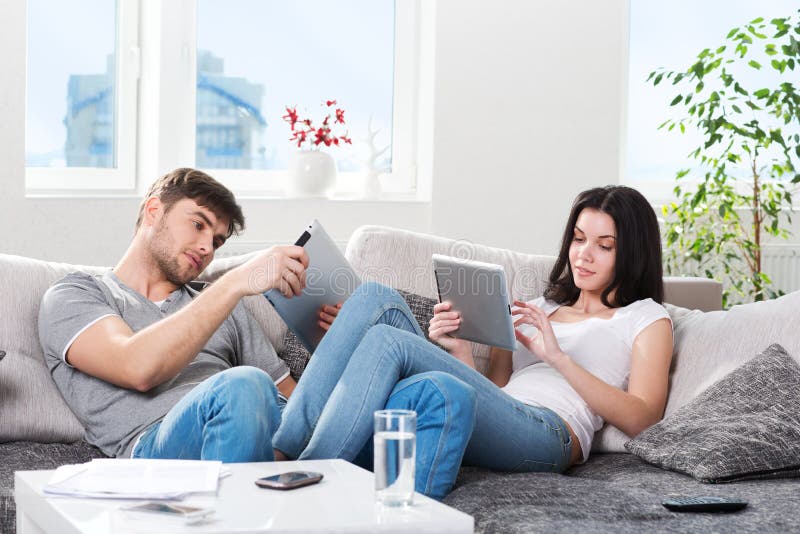 Couple Sitting on a Couch with Tablet Computers Stock Photo - Image of ...