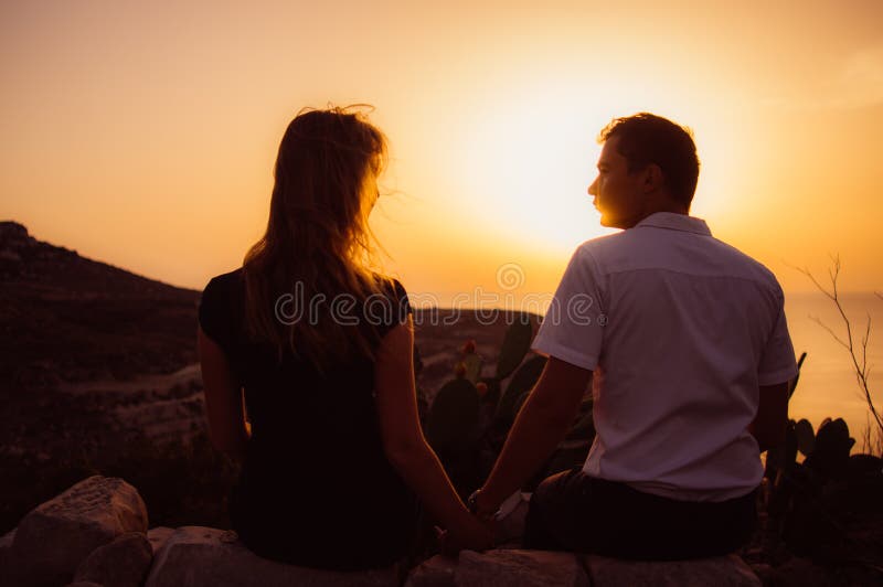 Couple Sitting on Rock in the Evening on the Seaside Stock Photo ...
