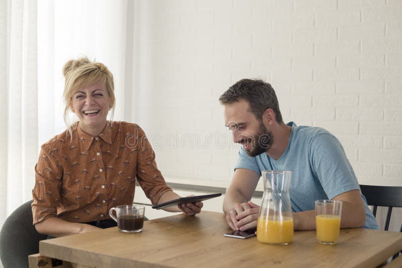 Couple Sitting by the Table. they are Having Fun Watching Something on ...
