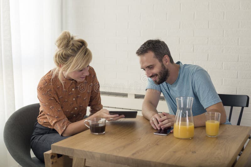 Couple Sitting by the Table. they are Having Fun Watching Something on ...