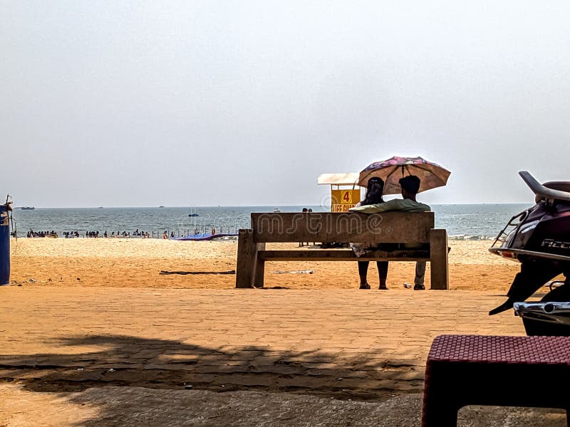 The Couple Sitting Under the Umbrella in the Sun on a Bench Editorial ...