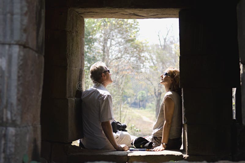 Couple Sitting in Window of Stone Building Stock Image - Image of ...