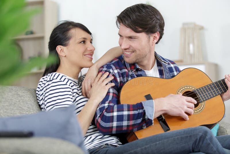 Couple Snuggled on Sofa while Man Plays Guitar Stock Image - Image of ...