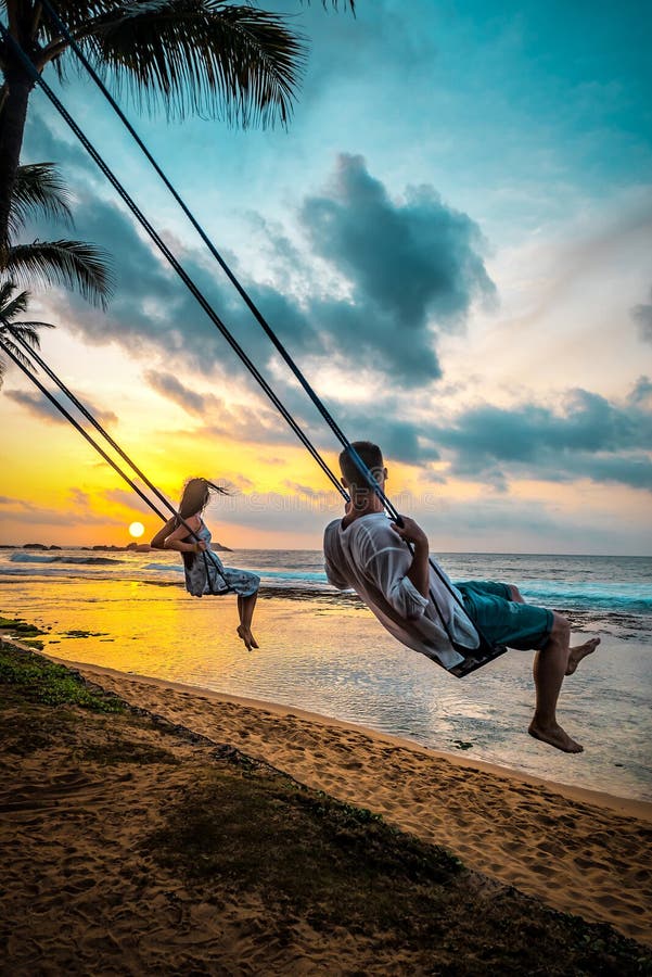 Couple on the Swing at Tropical Sunset Stock Photo - Image of ...
