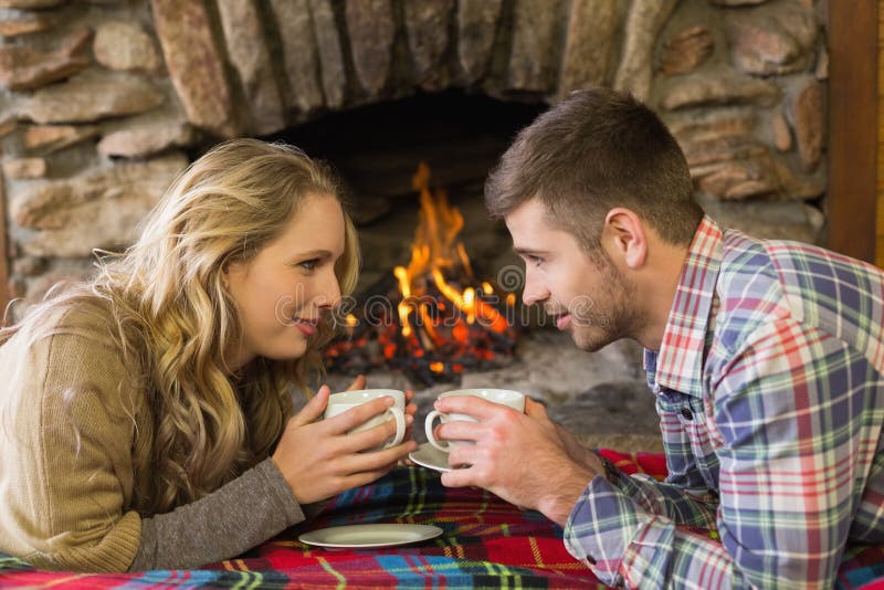 Couple with Tea Cups in Front of Lit Fireplace Stock Image - Image of ...