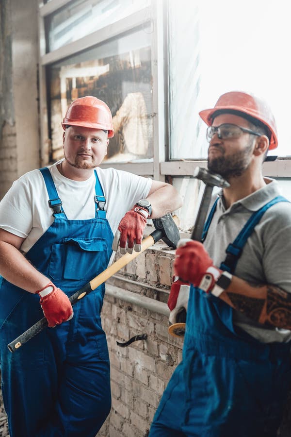 A Couple of Tired Workers Stand at a Large Window at a Construction ...