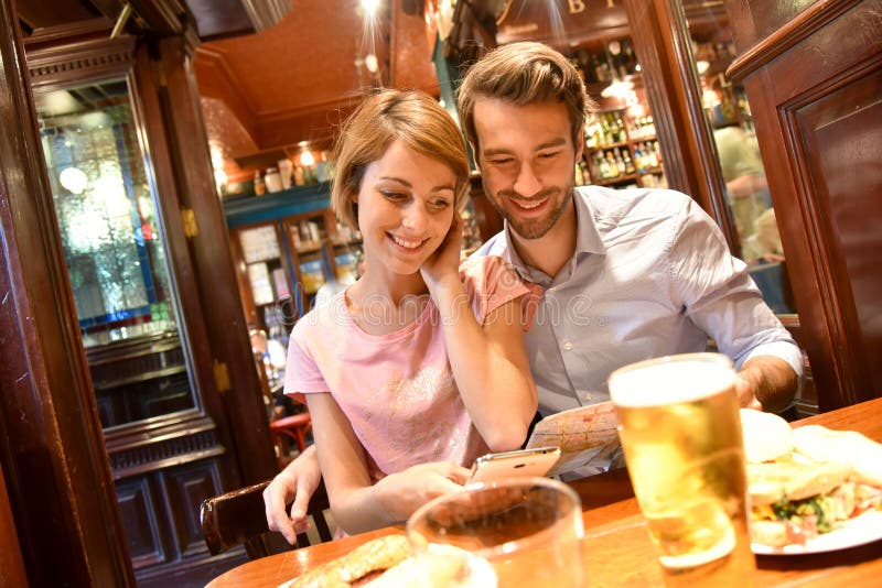 Couple of Tourists in Restaurant with Smartphone and Map Stock Photo ...