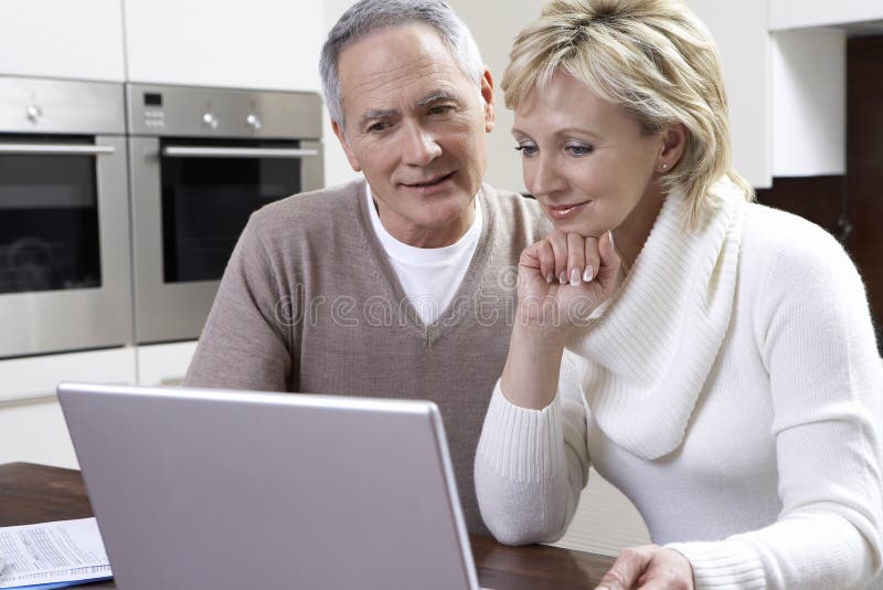 Couple Using Laptop at Kitchen Table Stock Photo - Image of casual ...