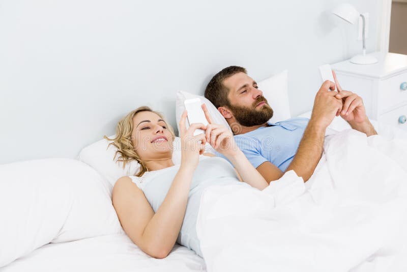 Couple Using Mobile Phone on Bed Stock Image - Image of cellphone ...