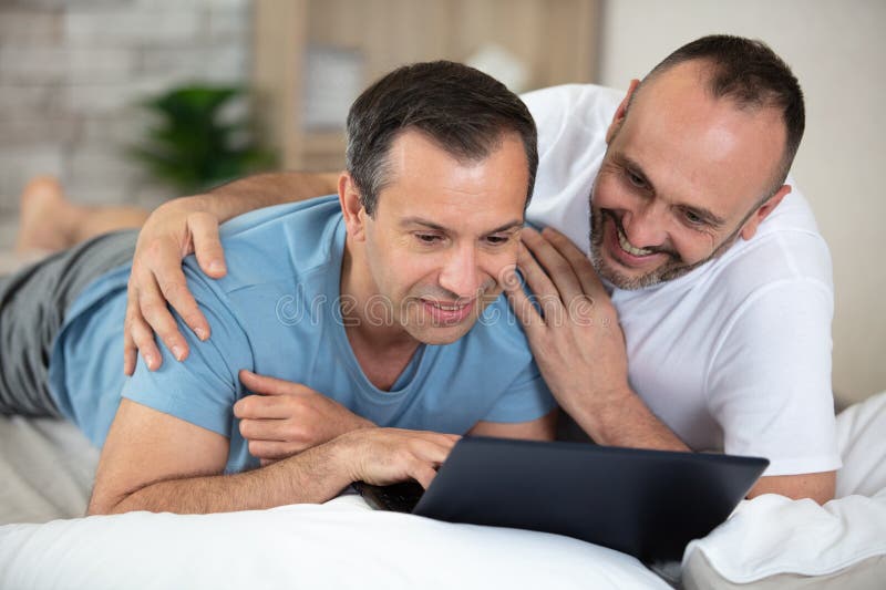 Couple using pc on bed stock photo. Image of homosexual - 285685246